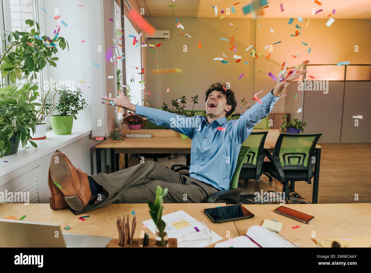 Cheerful businessman throwing confetti at desk in office Stock Photo ...