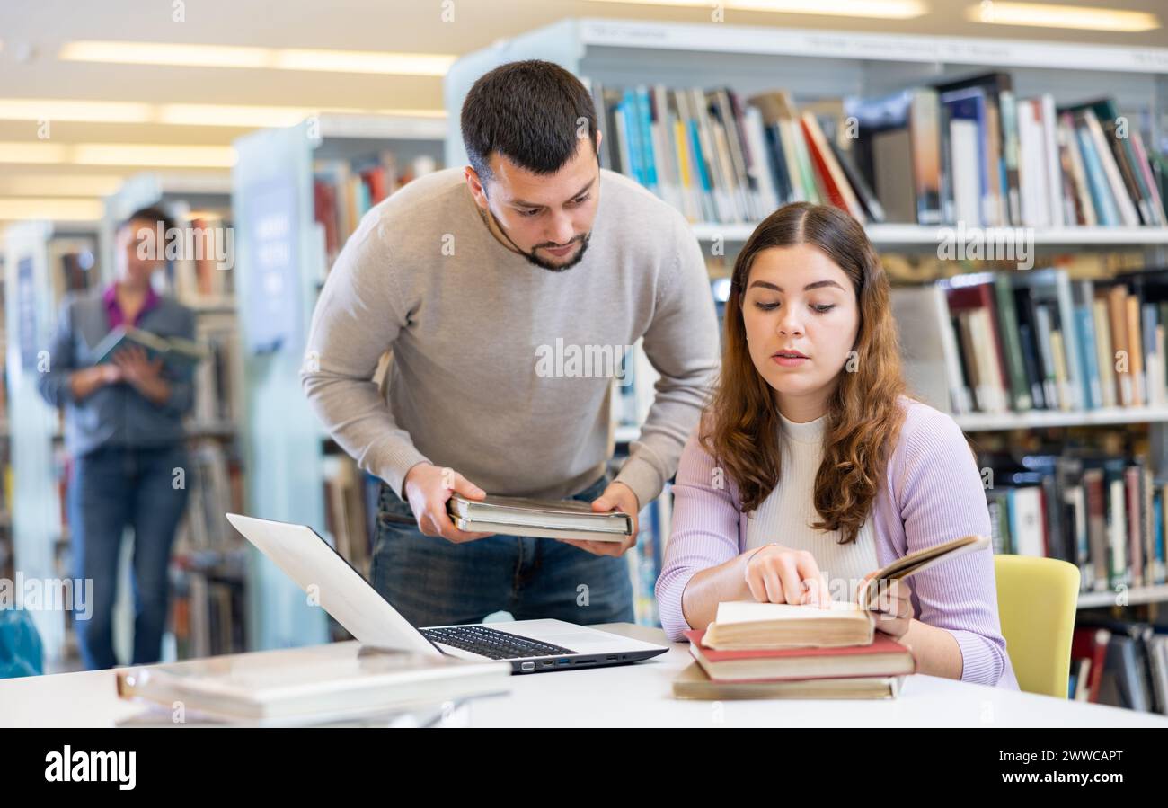 Man recommending books to woman in public library Stock Photo - Alamy