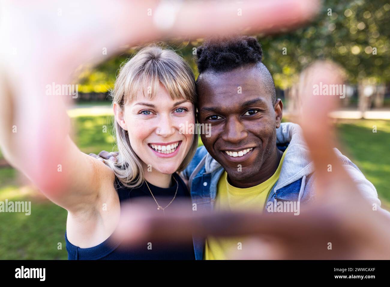 Smiling friends making finger frame gesture at park Stock Photo - Alamy