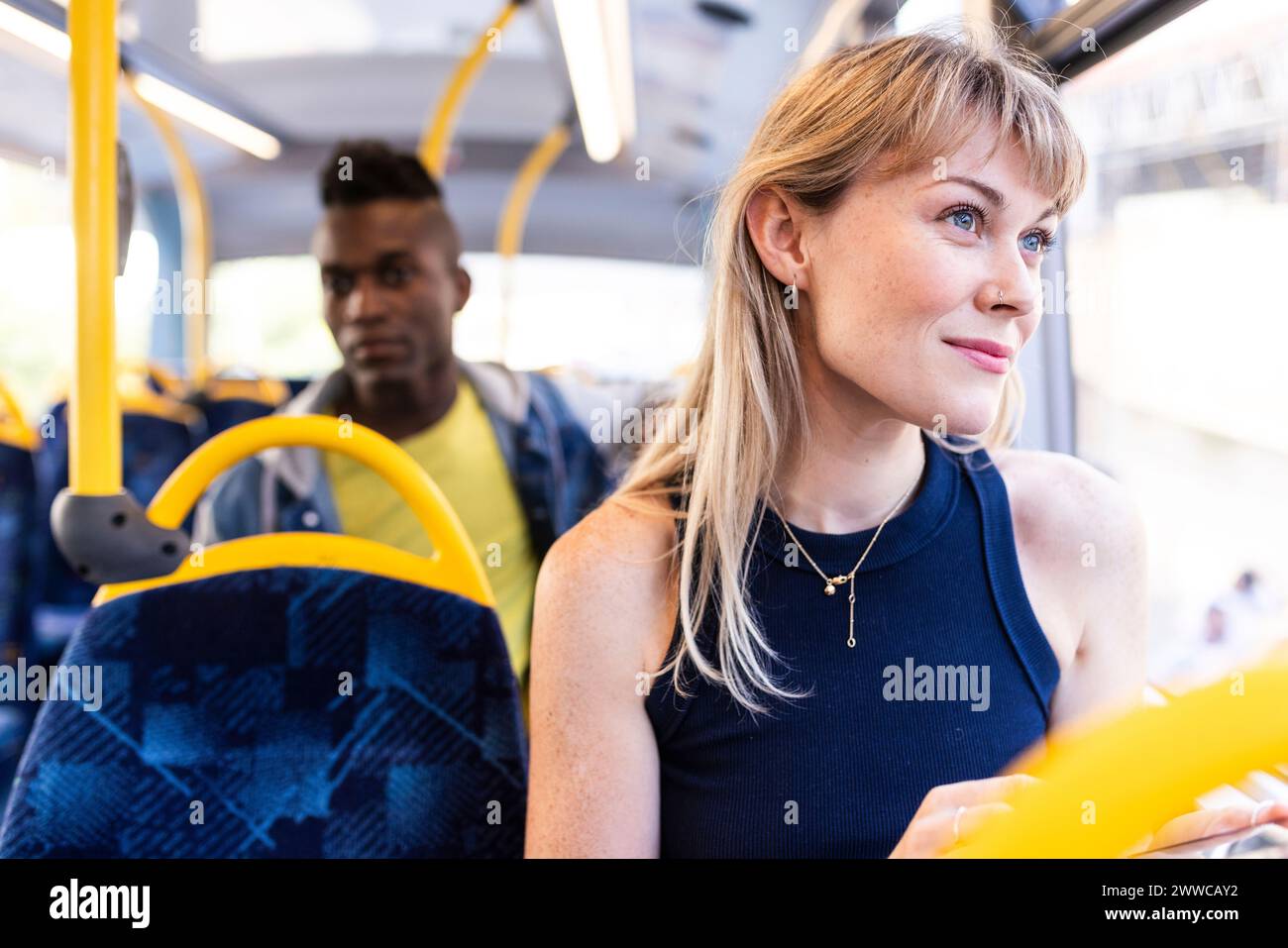 Smiling woman looking out of window sitting with friend in bus Stock ...