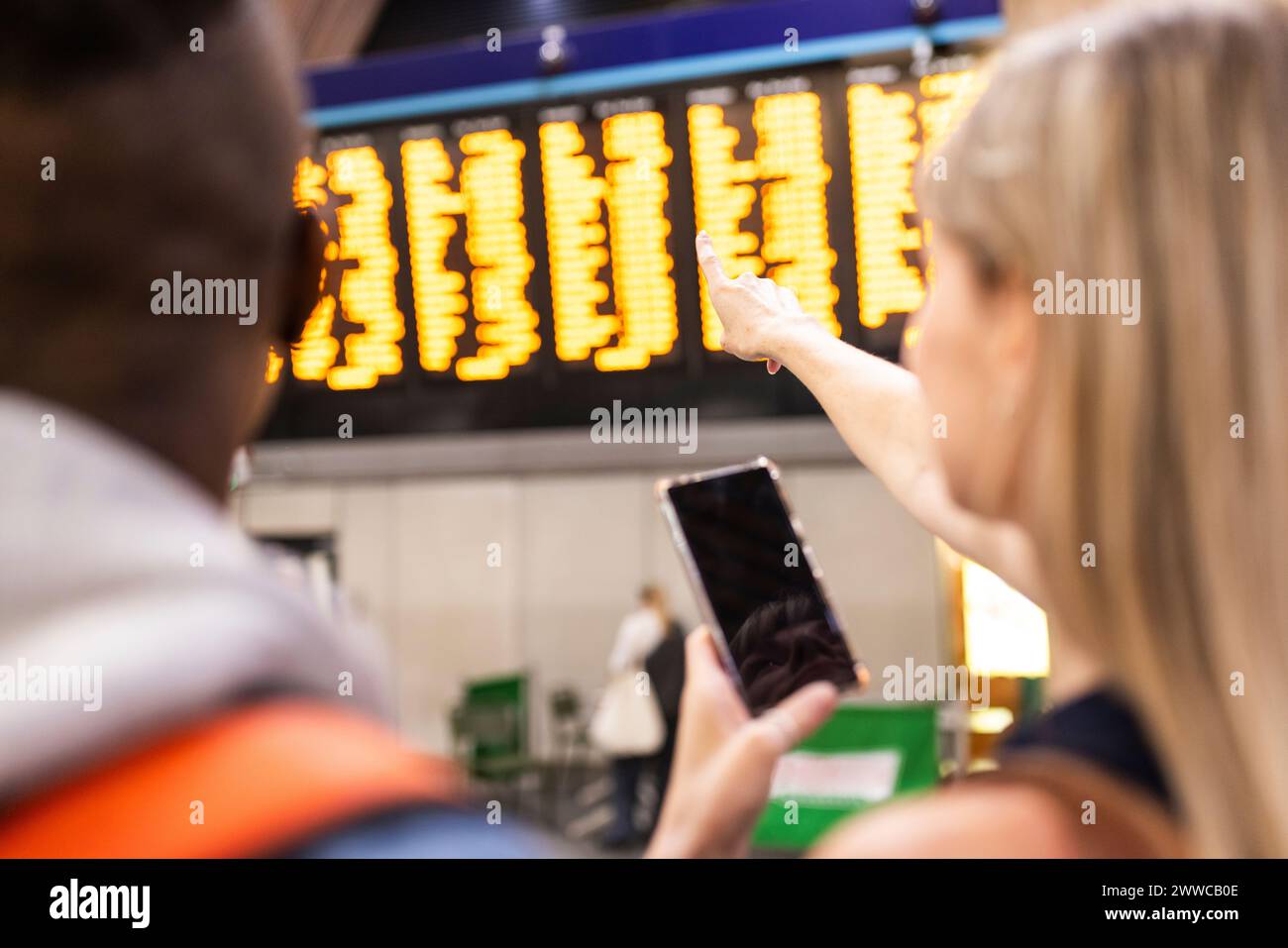 Woman checking train timetable holding smart phone at station Stock ...