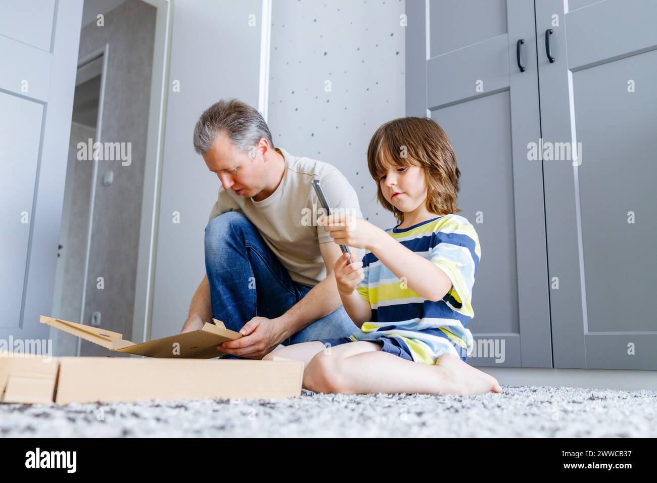 Boy and father assembling bedside table at home Stock Photo - Alamy