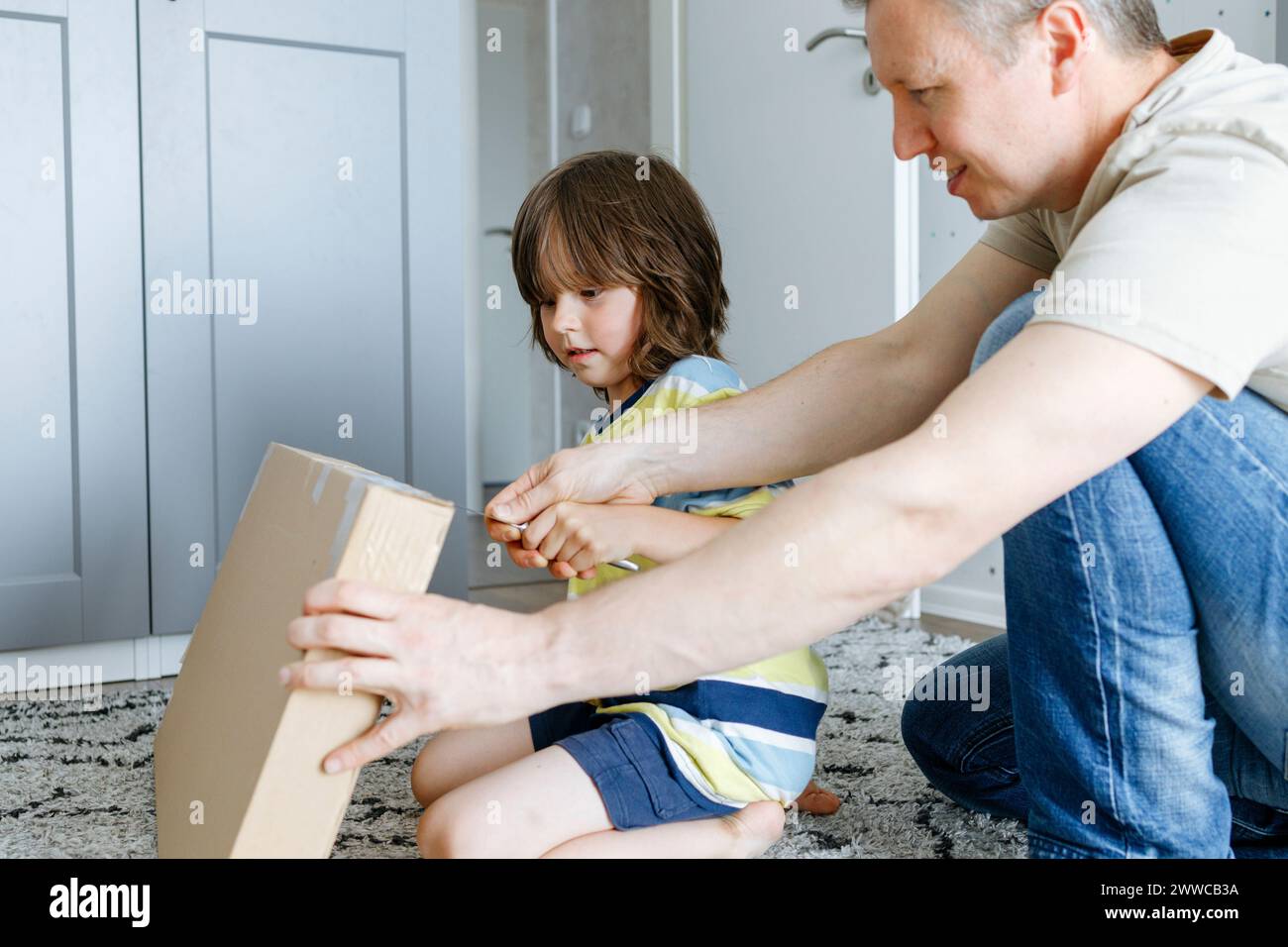 Dad and son opening box at home Stock Photo - Alamy