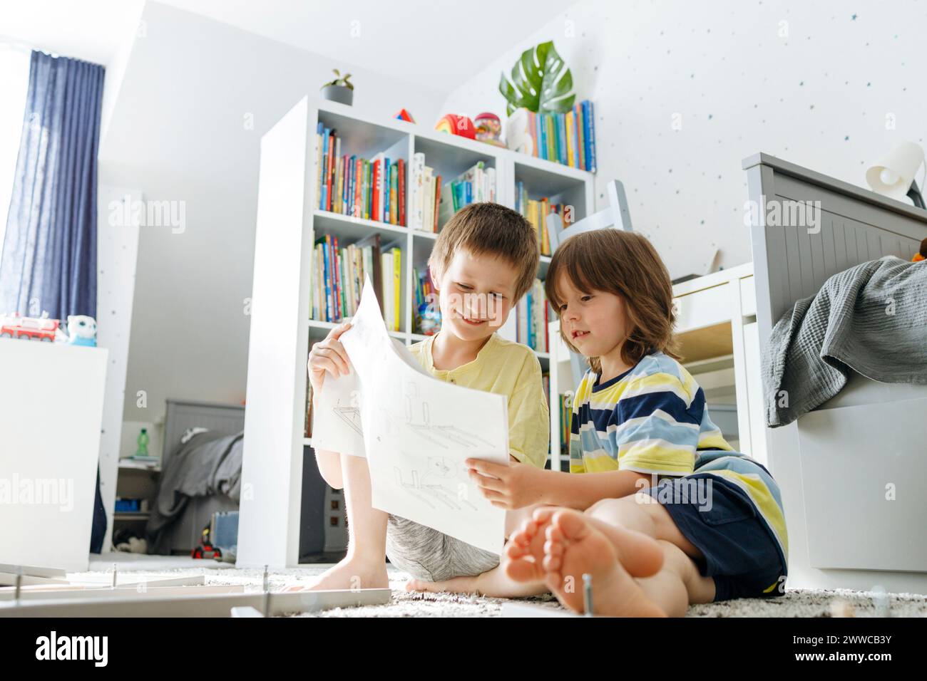 Brothers reading manual before assembling furniture at home Stock Photo ...