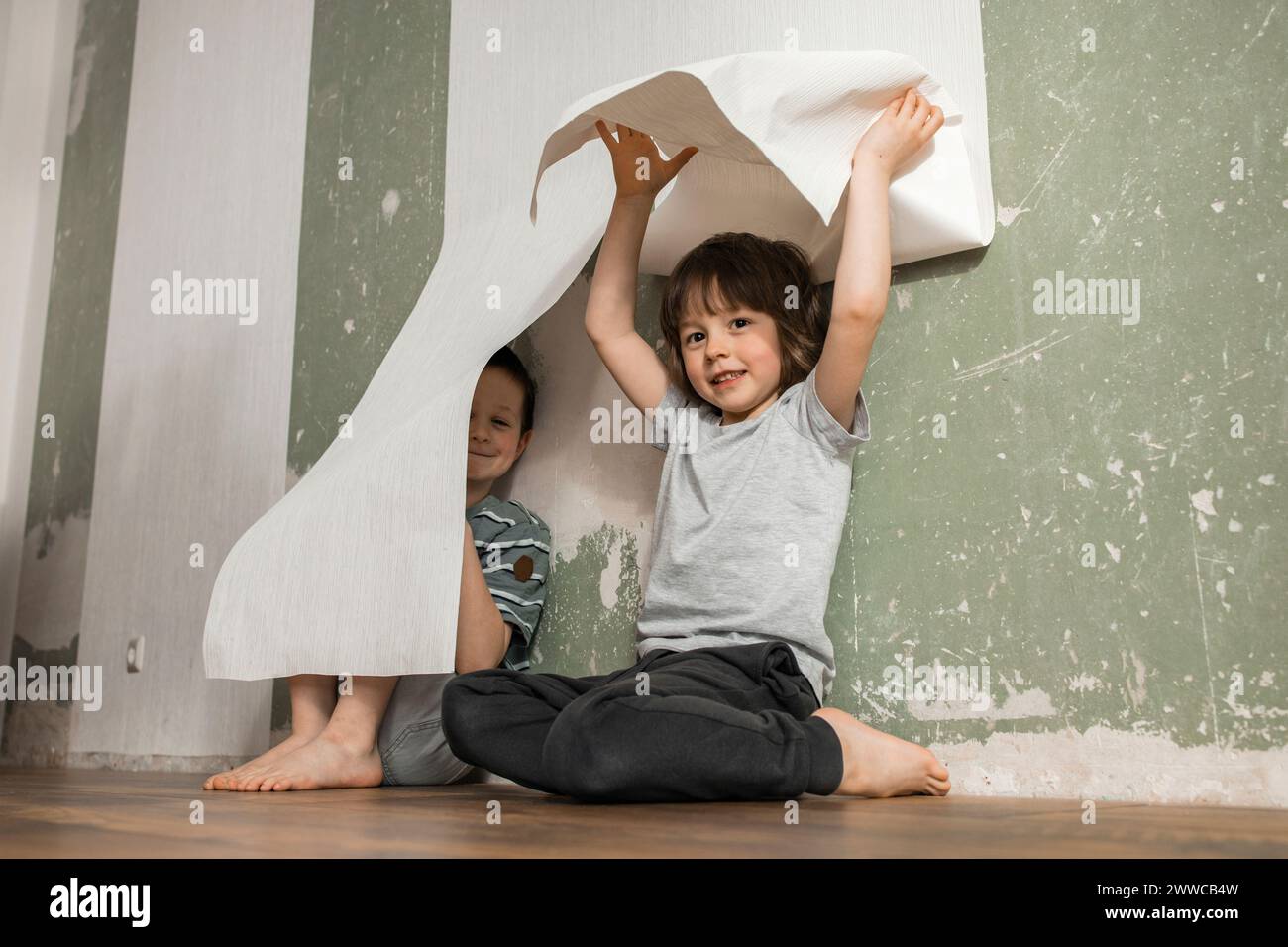 Brothers hiding under white wallpaper at home Stock Photo - Alamy
