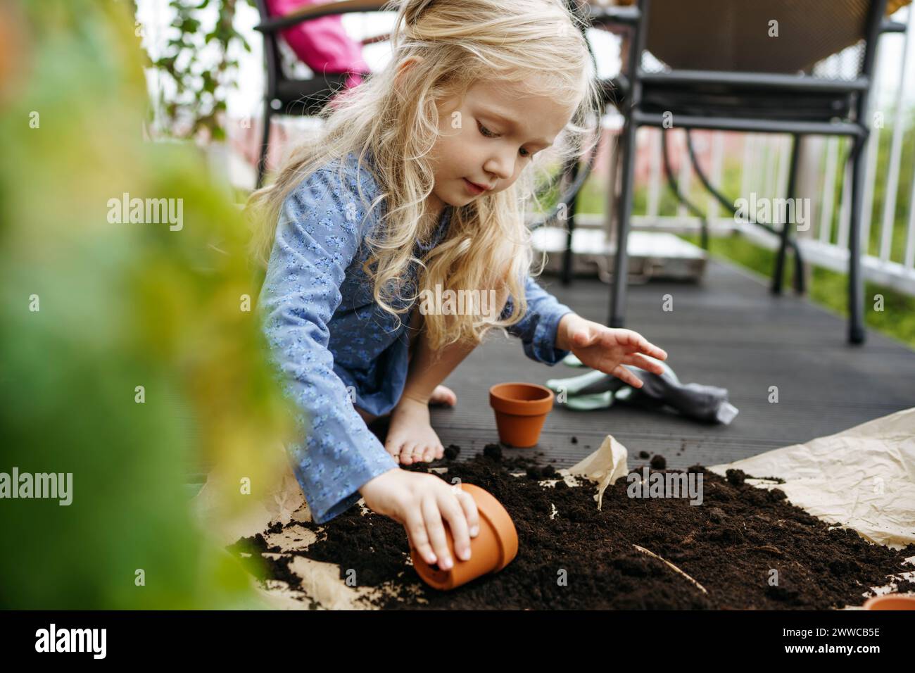 Girl filling pot with dirt and fertilizer in balcony Stock Photo - Alamy