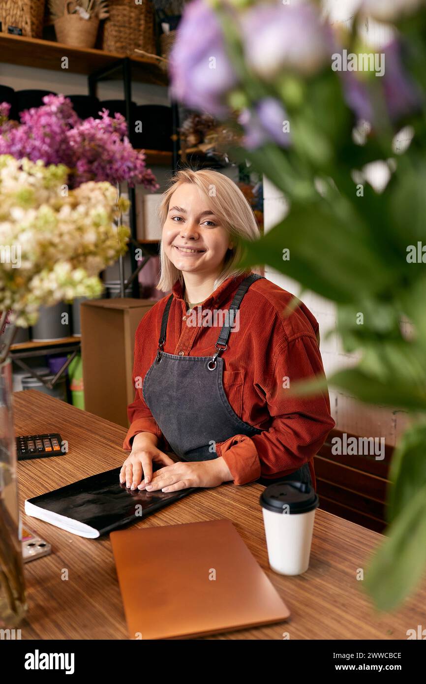 Happy florist standing with diary at reception desk Stock Photo - Alamy
