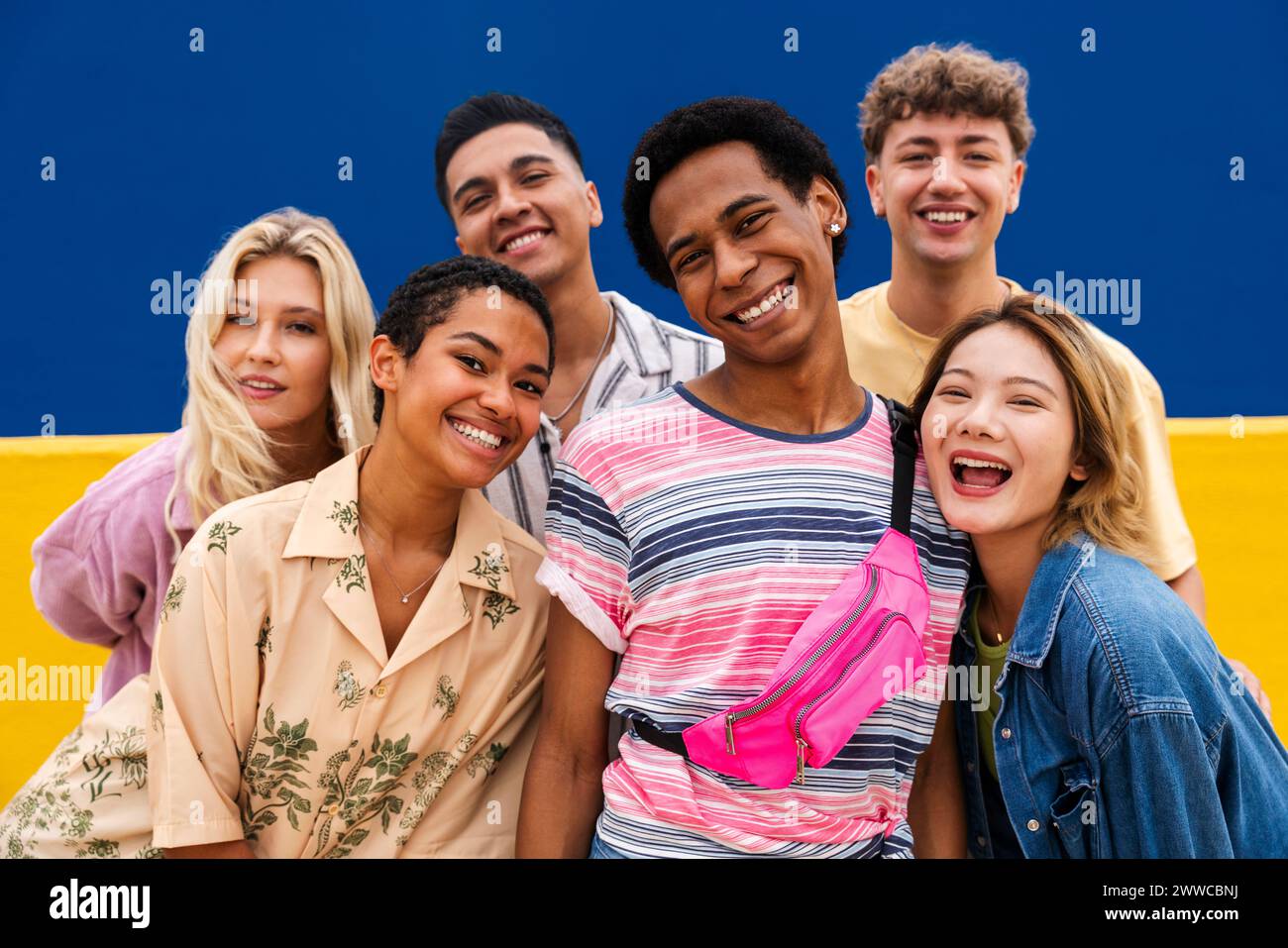 Portrait of laughing multi-ethnic friends against yellow wall Stock ...