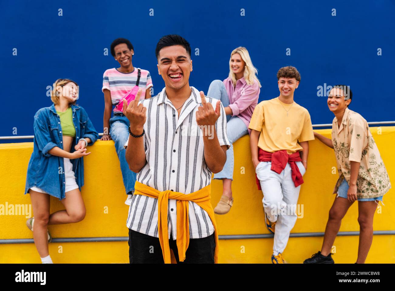 Confident young man standing in front of group of friends showing ...