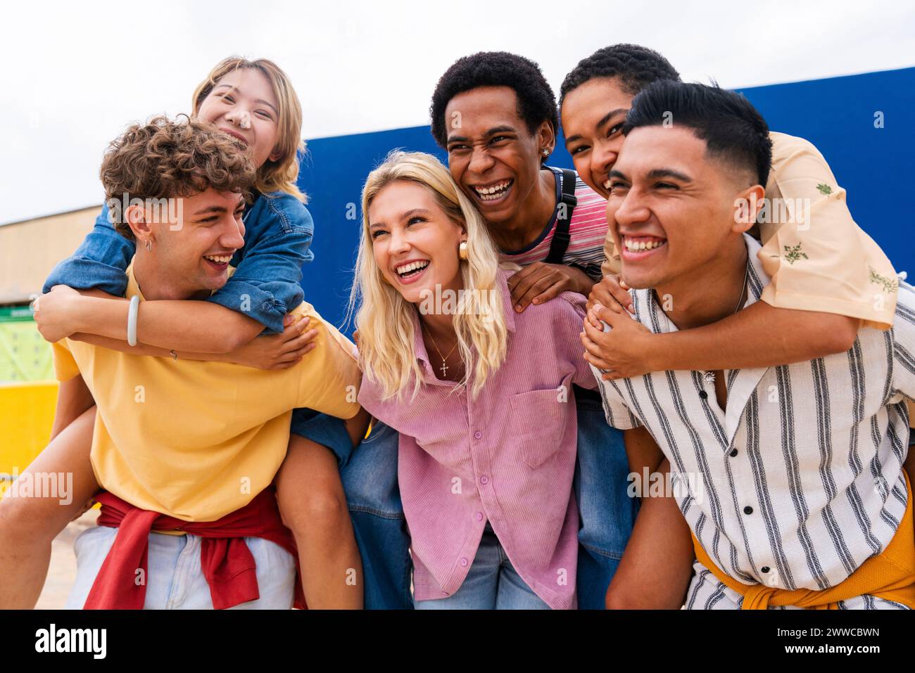 Laughing friends carrying each other piggyback Stock Photo - Alamy