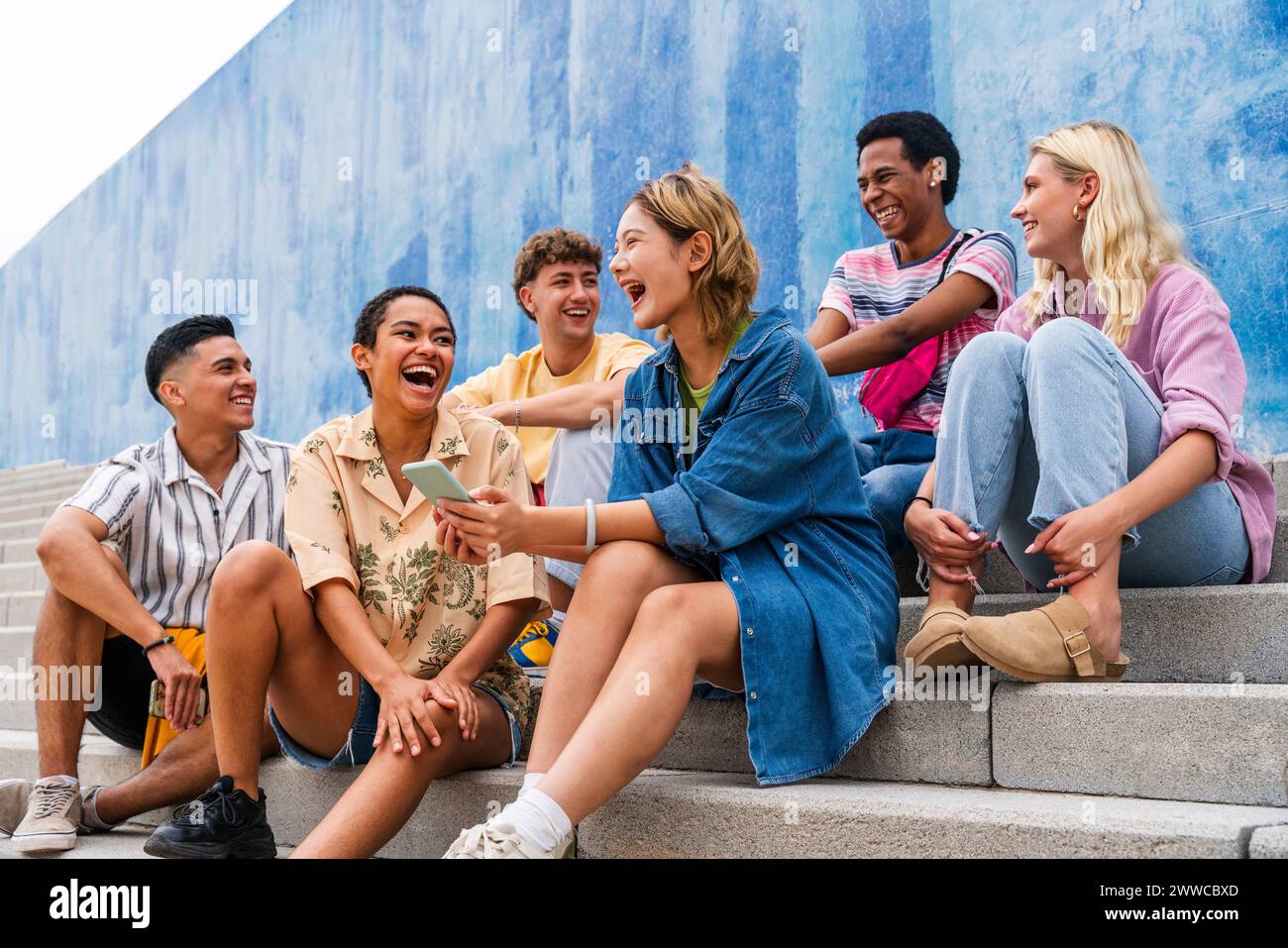 Happy group of young people laughing on steps in front of wall Stock ...