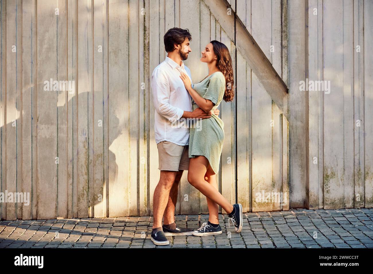 Loving young couple standing in front of wall Stock Photo - Alamy
