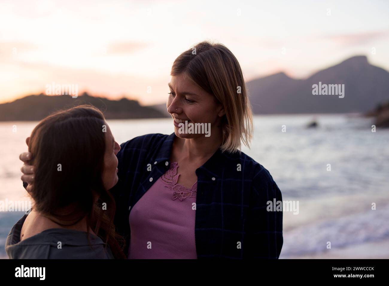 Happy friends talking at sunset beach on vacation Stock Photo - Alamy