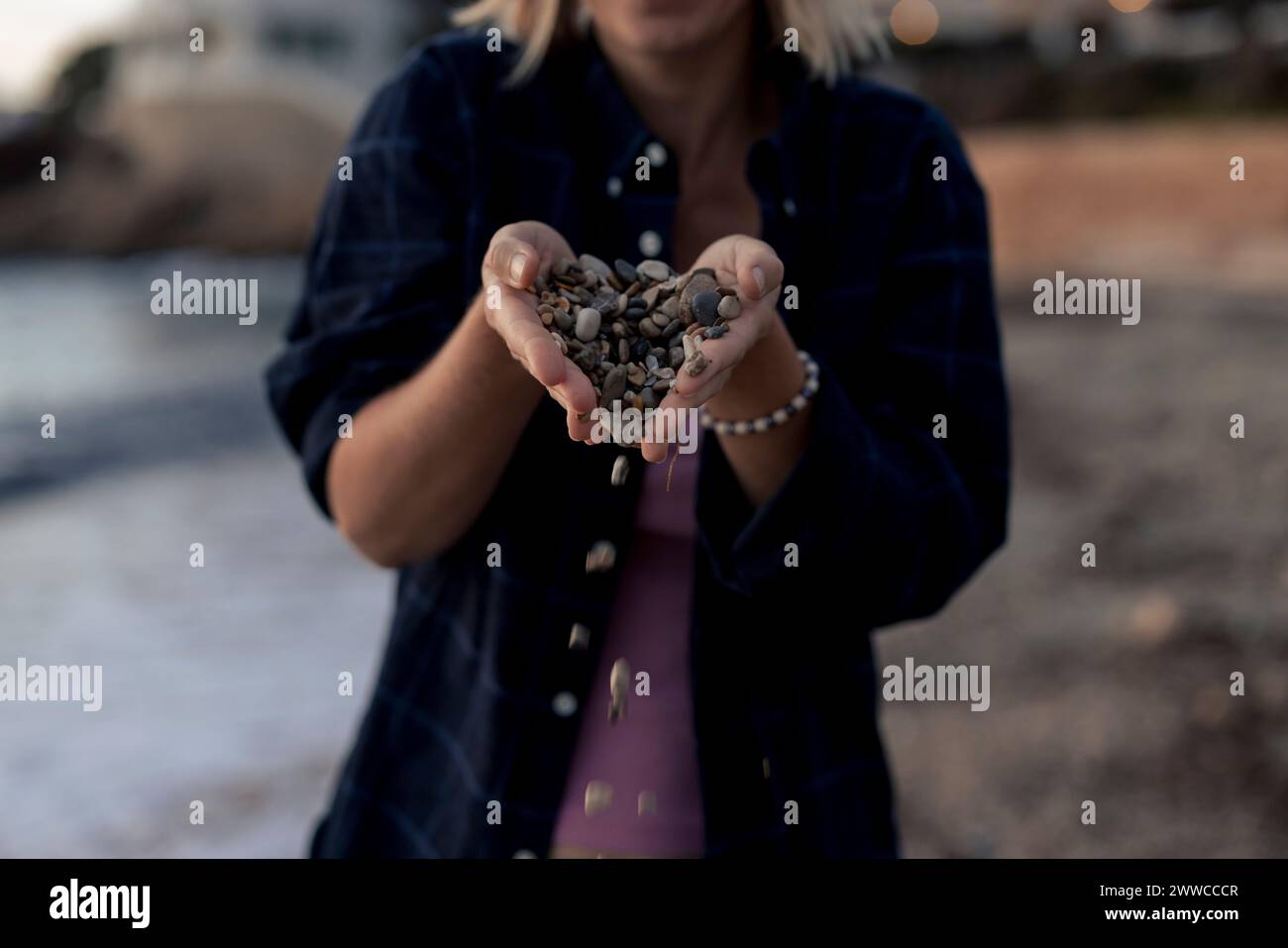 Woman throwing pebbles with hands cupped at sunset beach Stock Photo ...