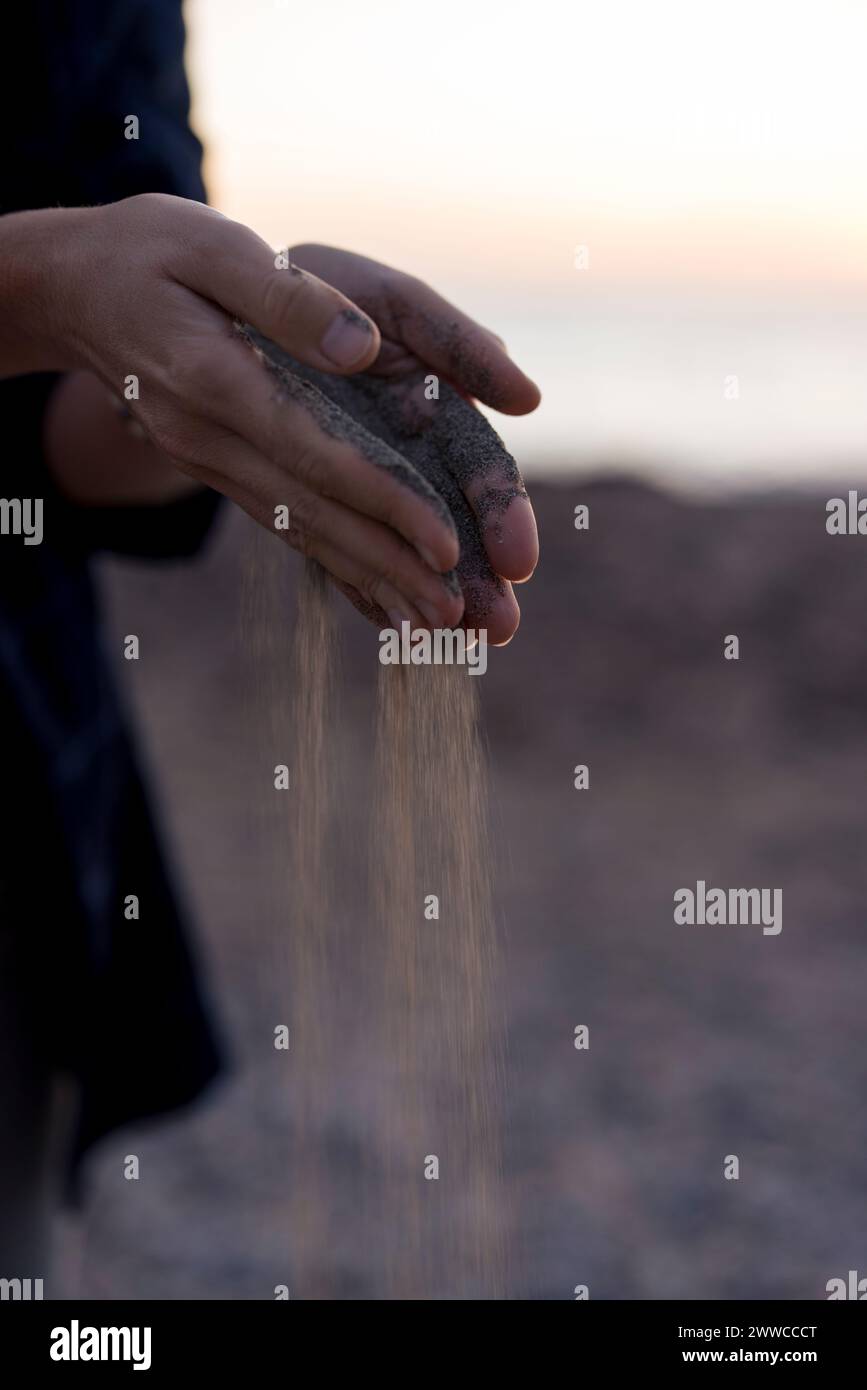 Woman throwing sand with hands cupped at sunset beach Stock Photo - Alamy