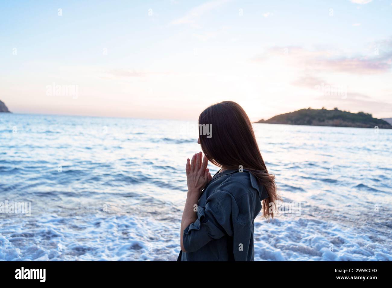 Woman with hands clasped at sunset beach Stock Photo - Alamy