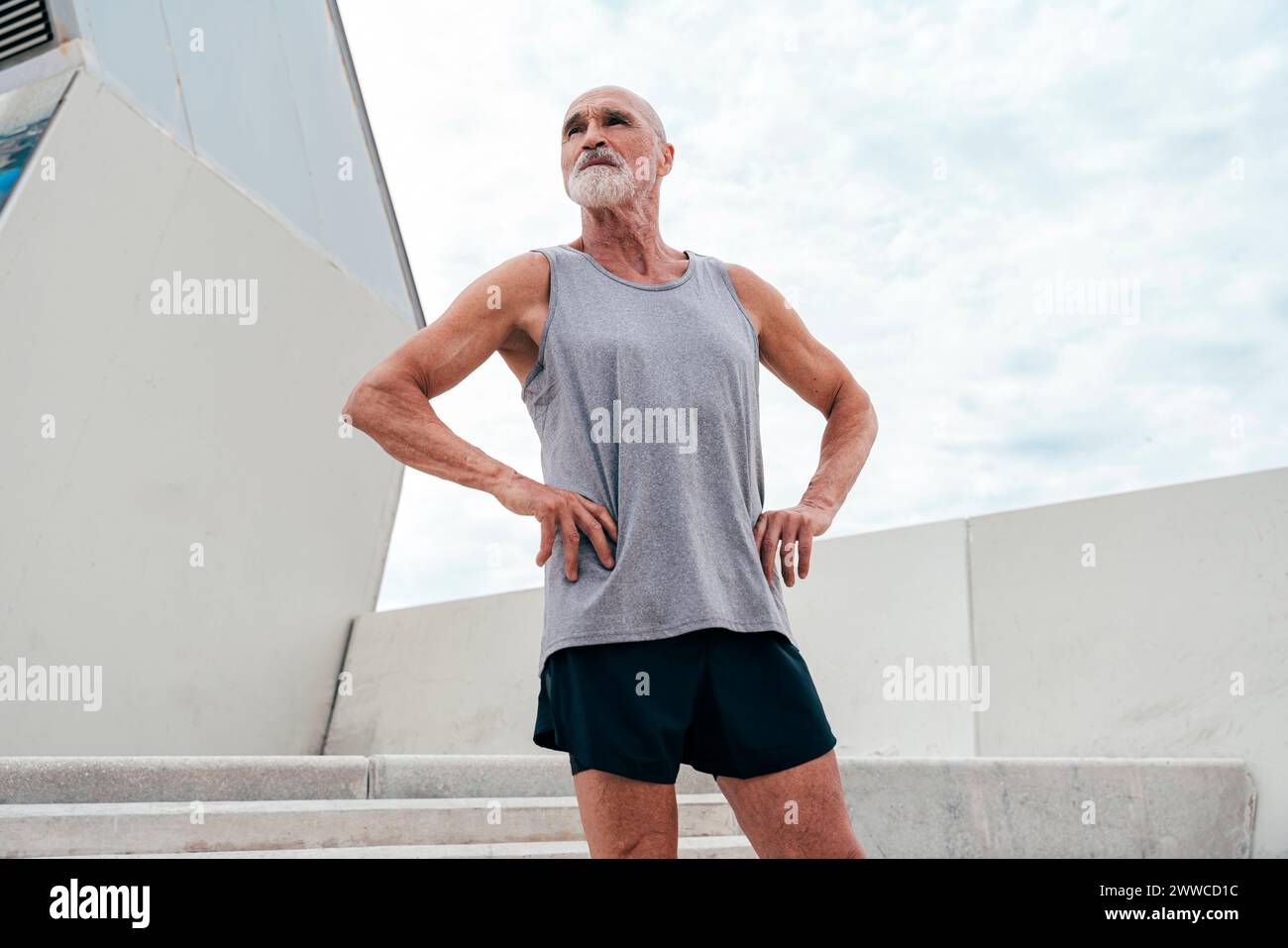 Retired senior man standing with arms akimbo Stock Photo - Alamy