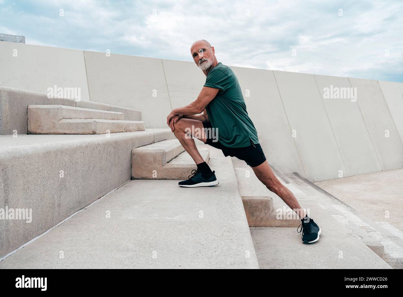 Confident active senior man stretching on steps Stock Photo - Alamy