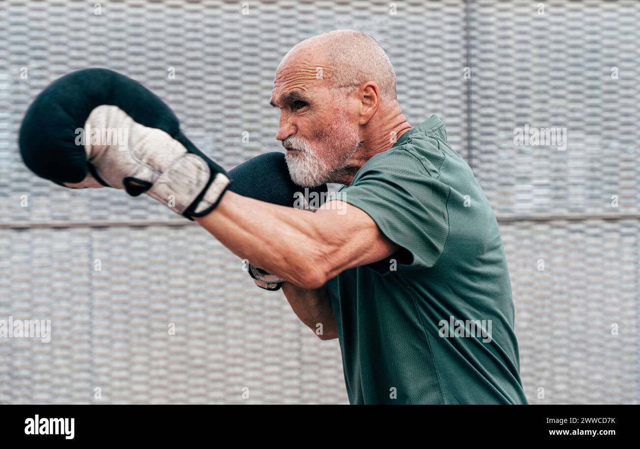 Confident active senior man practicing with boxing gloves in front of ...