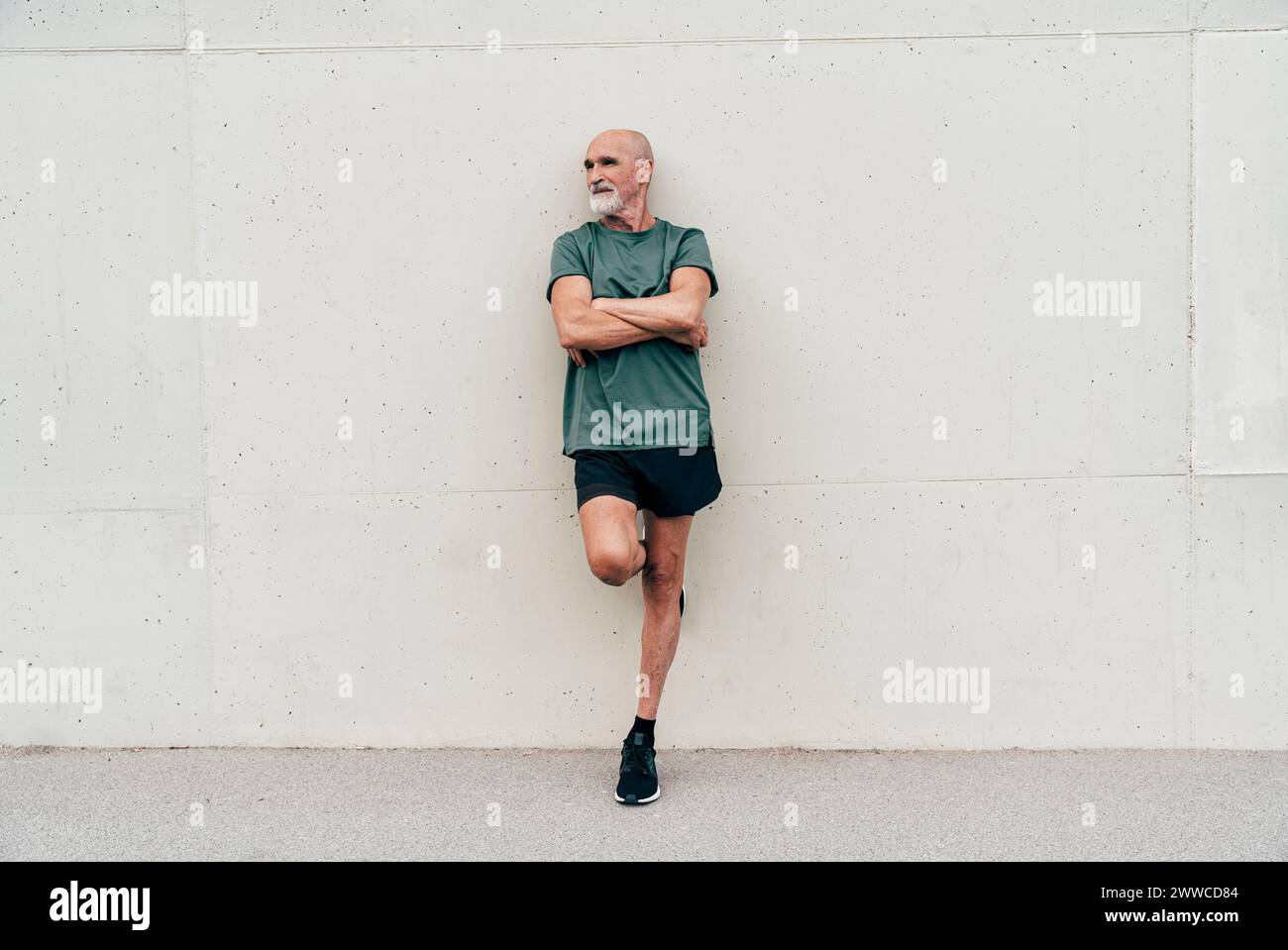 Retired man with arms crossed leaning on wall Stock Photo - Alamy