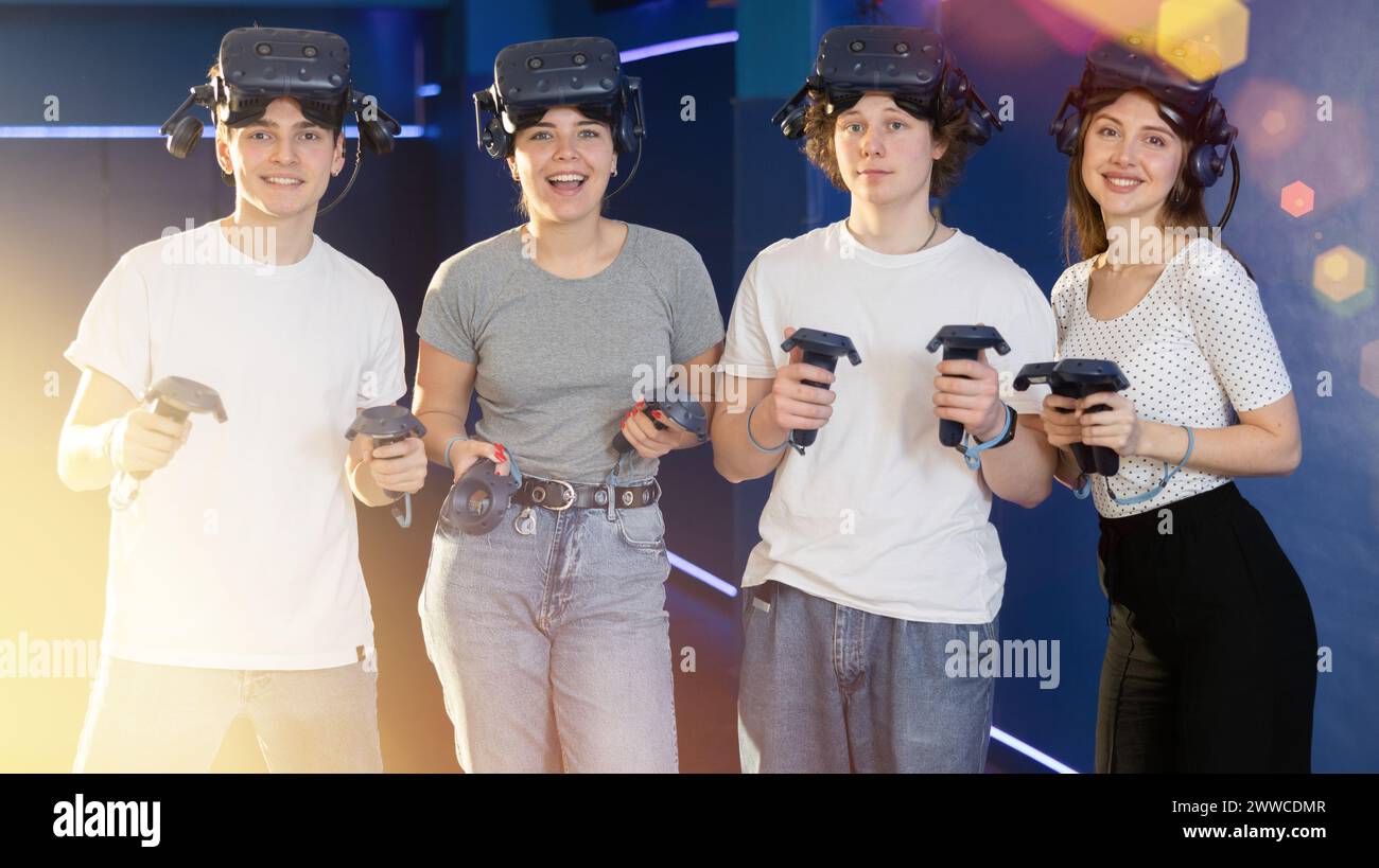 four smiling students with virtual reality devices stand and pose in ...