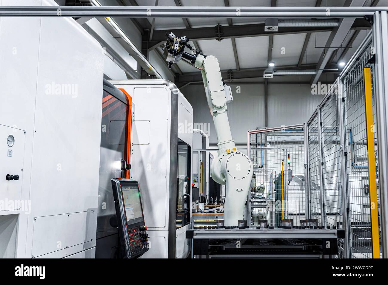 White robotic arm by CNC machinery in modern manufacturing factory ...
