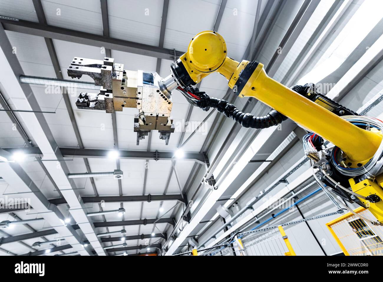 Yellow robotic arm in illuminated modern factory Stock Photo - Alamy