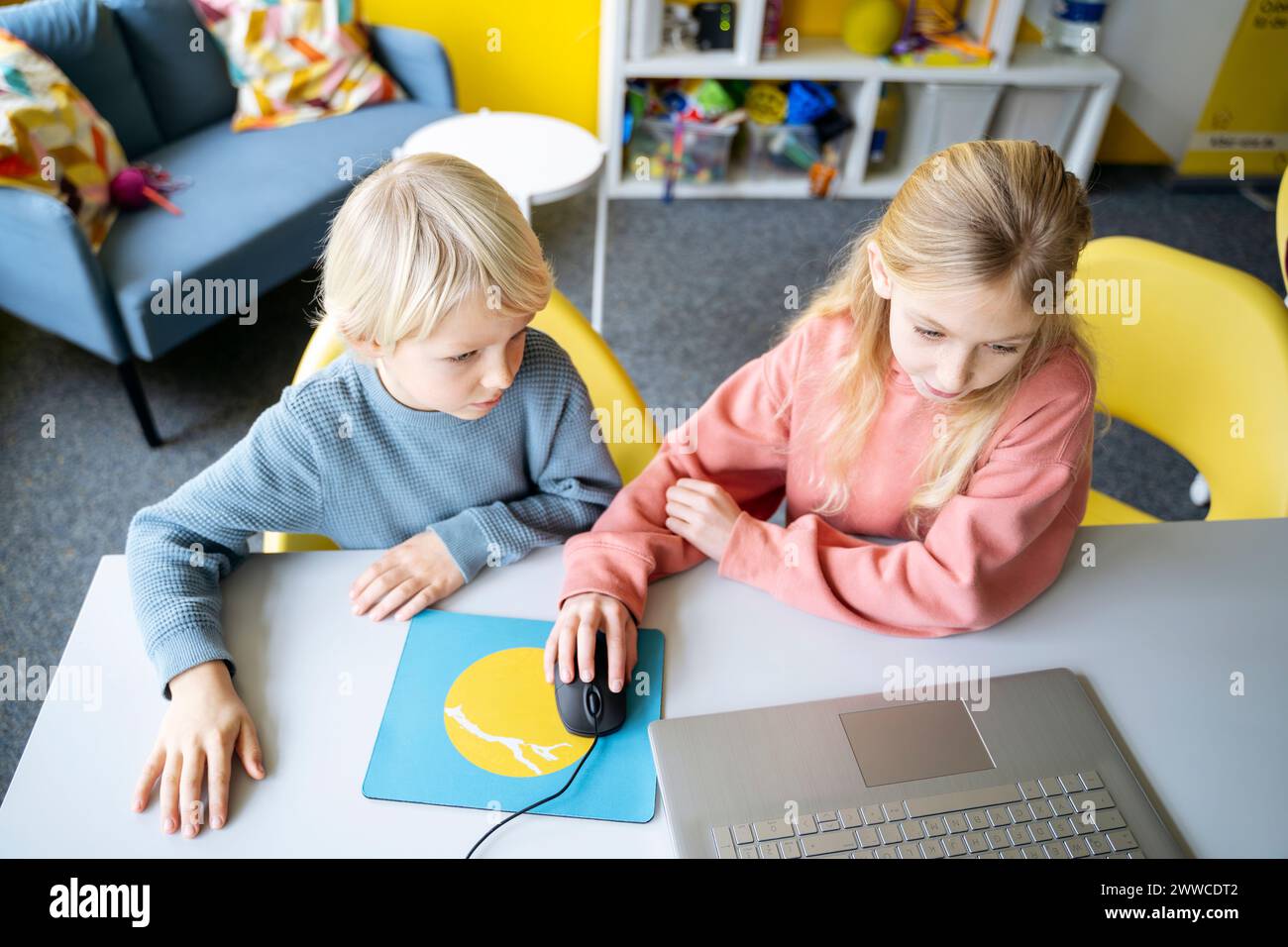 Girl and boy sharing laptop for learning computer coding in classroom ...