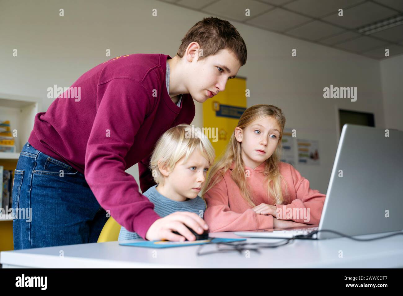 Teenage boy assisting students with coding in school classroom Stock ...