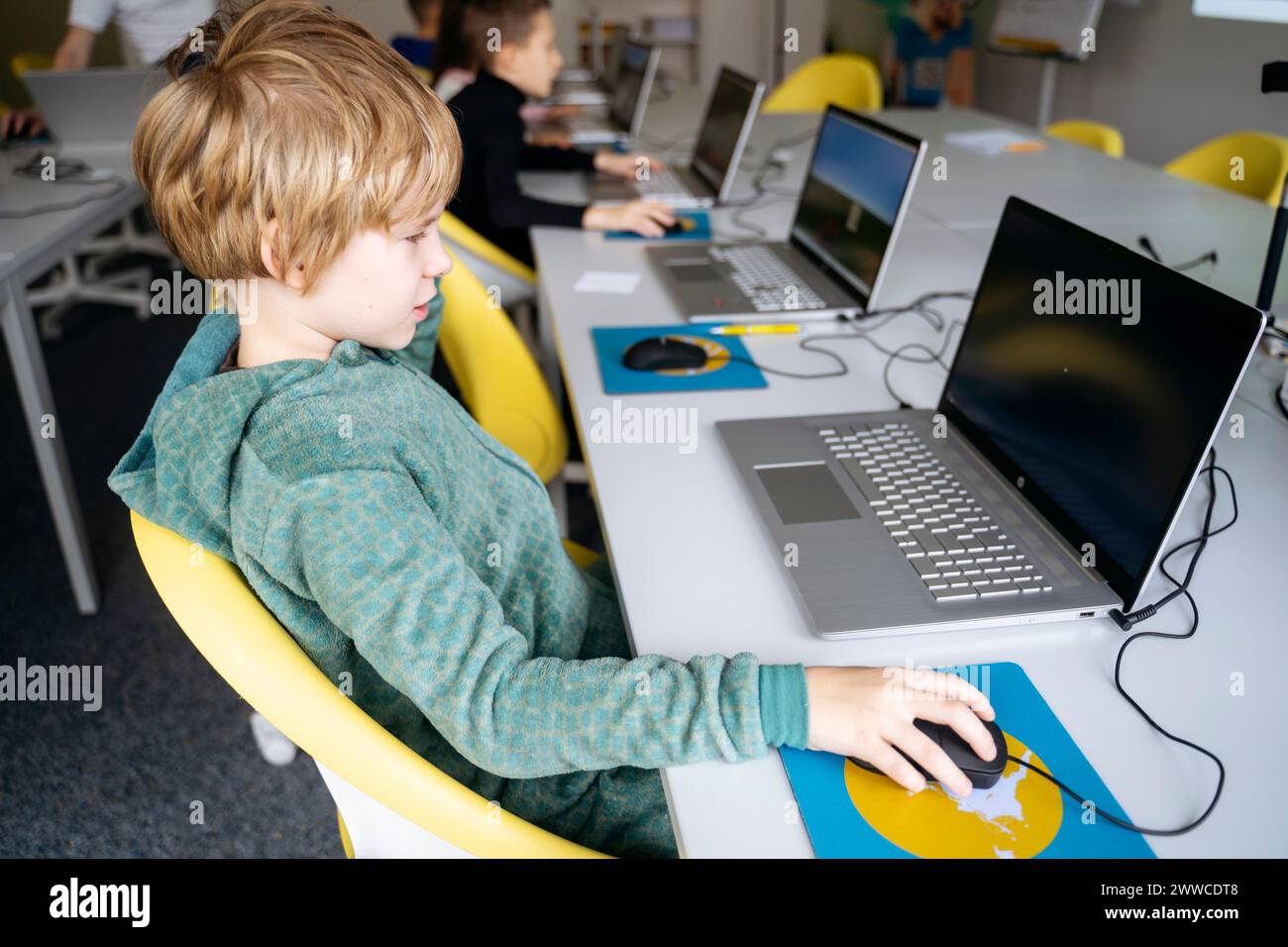 Blond boy learning computer codes in classroom Stock Photo - Alamy