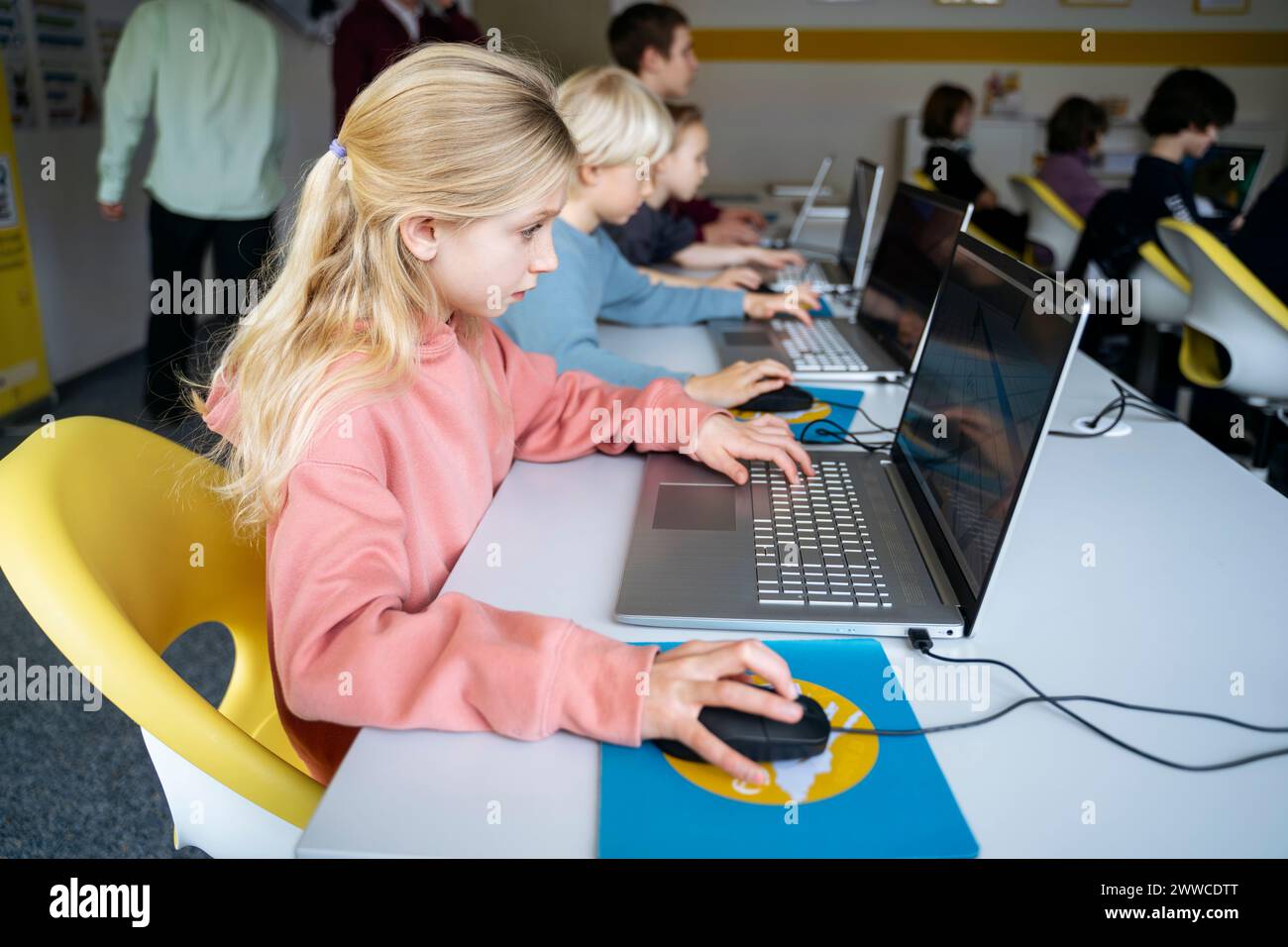 Dedicated blond girl using laptop learning computer at desk in ...