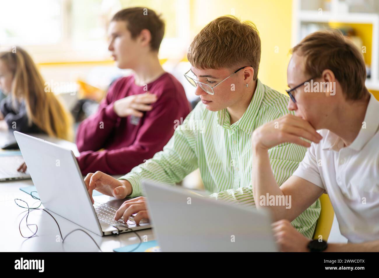 Teenage boy using laptop by professor in classroom Stock Photo - Alamy
