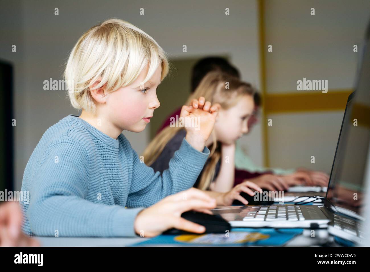 Blond boy learning coding through laptop desk in classroom Stock Photo ...