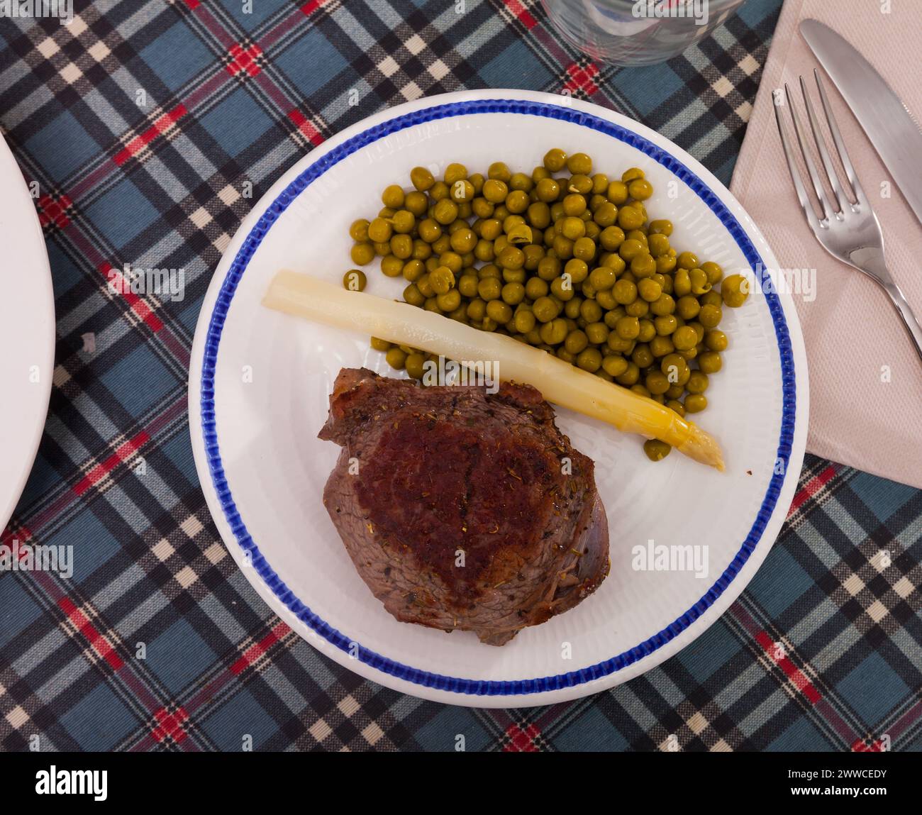 Beef cutlet with green peas on plate Stock Photo - Alamy