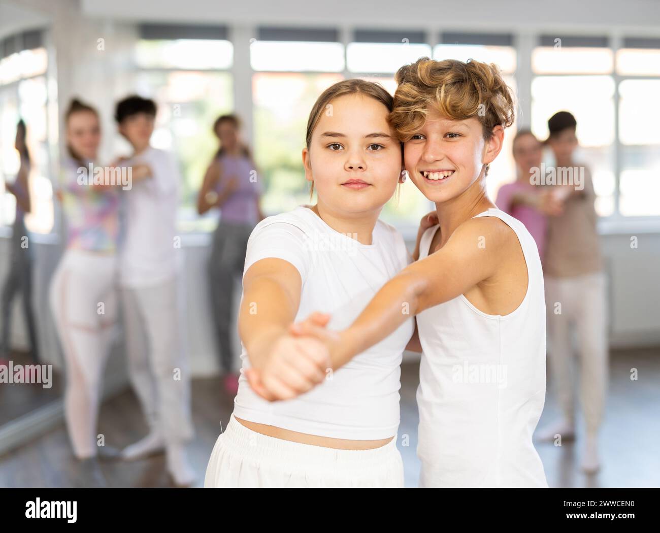 Group of positive teenagers learning to dance tango in dance studio ...