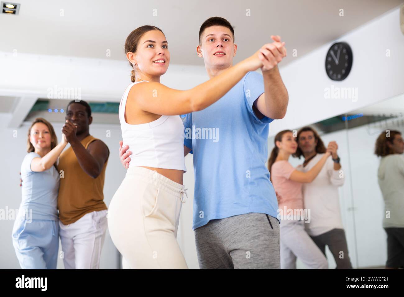 Woman and man practicing modern dance moves in pair during group class ...