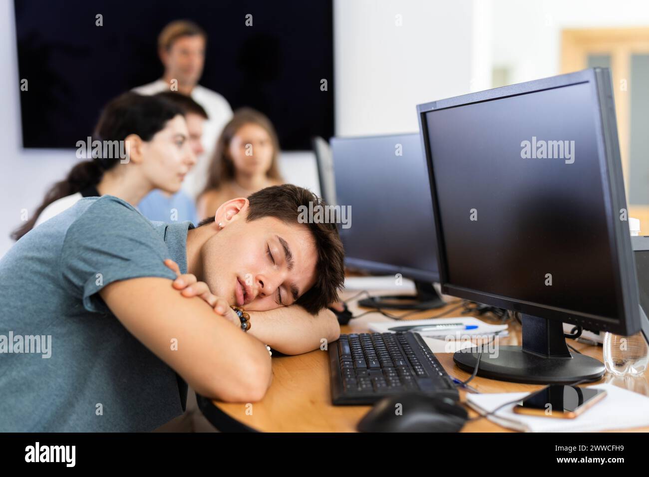 Exhausted young employee engaged in software development sleeping at ...