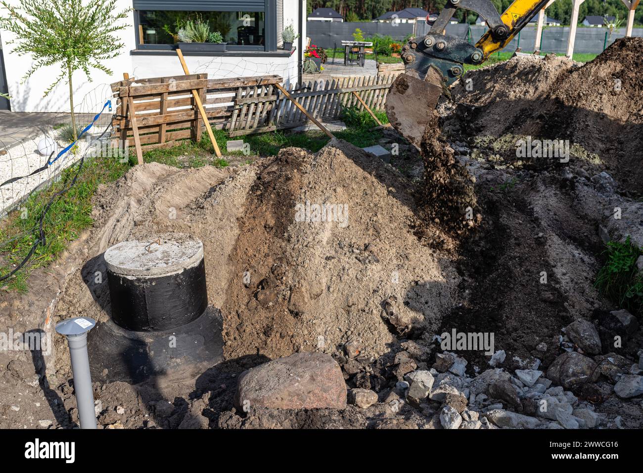 Using an excavator to bury a 10 m3 concrete septic tank located in the ...