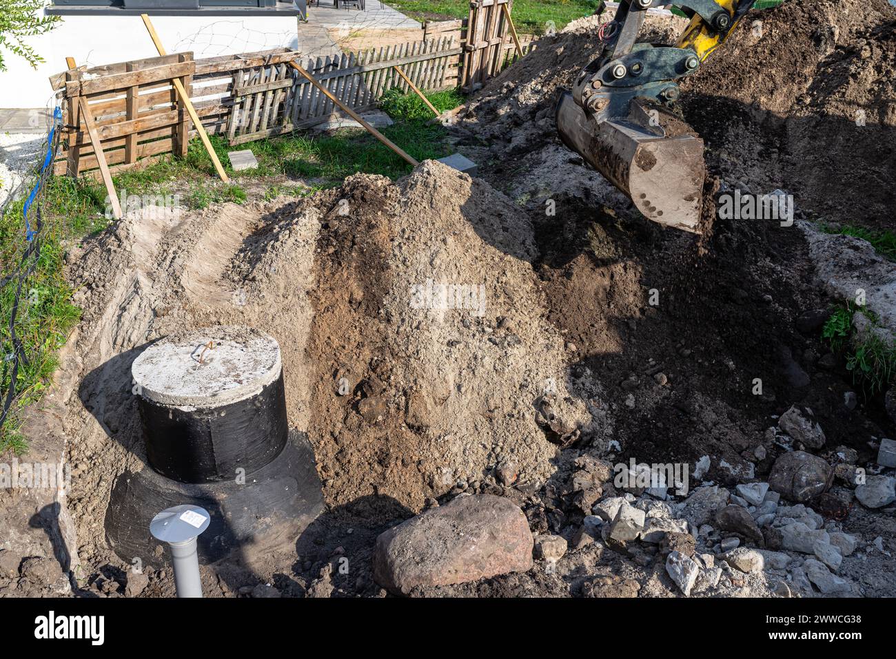 Using an excavator to bury a 10 m3 concrete septic tank located in the ...