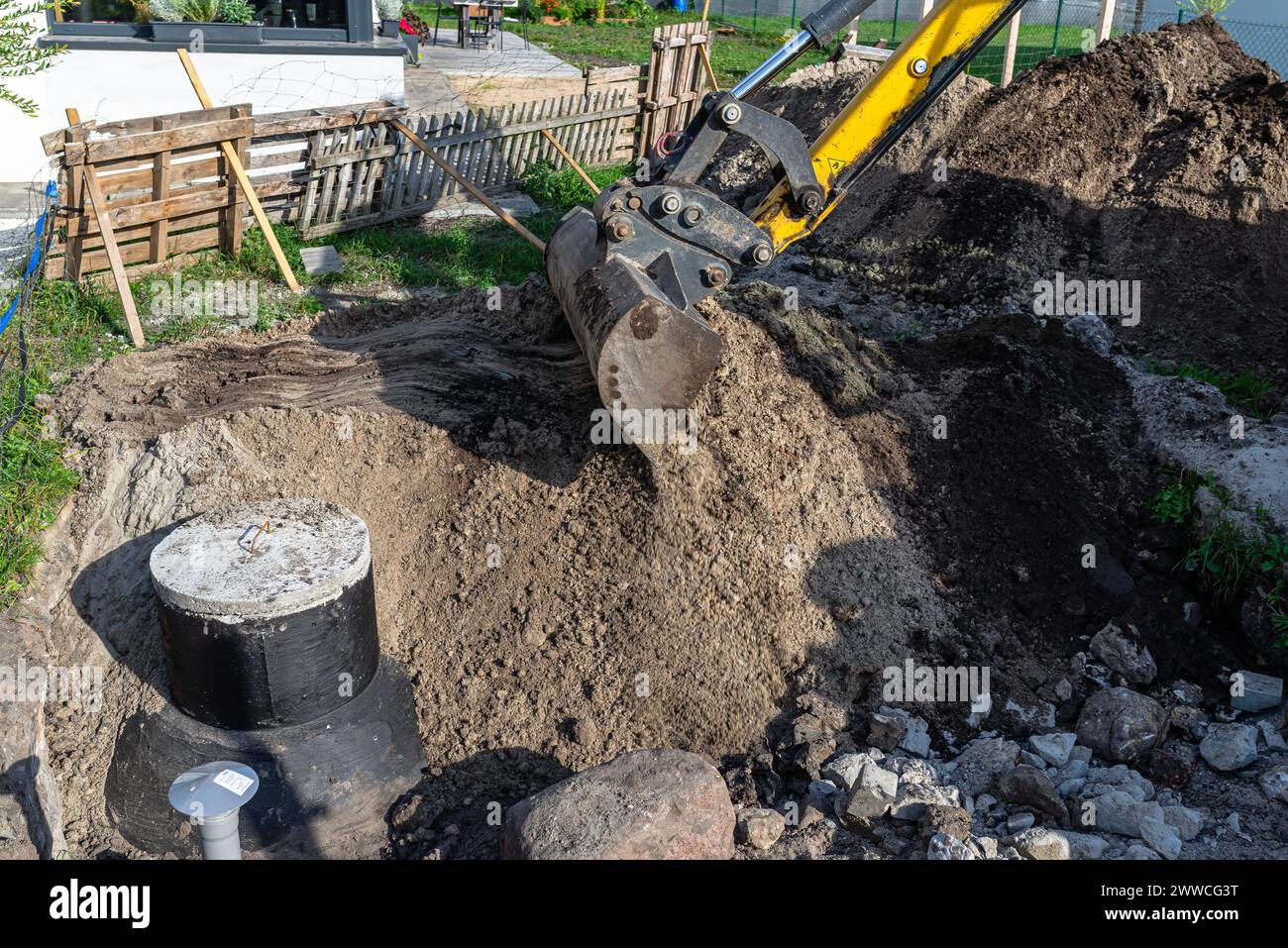 Using an excavator to bury a 10 m3 concrete septic tank located in the ...