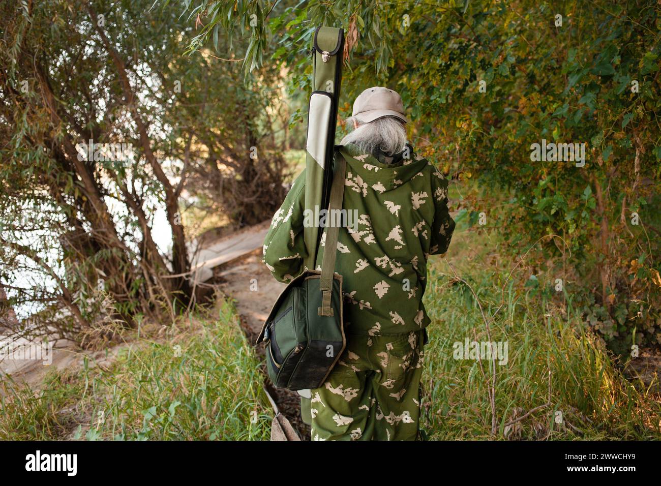 A man gray-haired fisherman is looking for a place to fish, goes ...