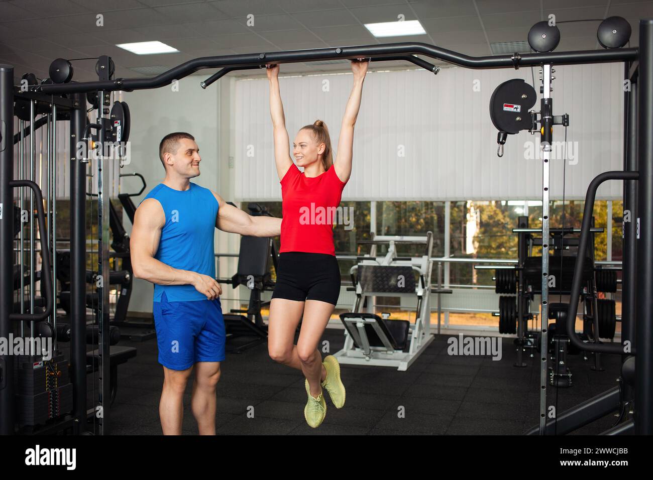 teenager performs an exercise on a simulator in gym. girl hangs on ...