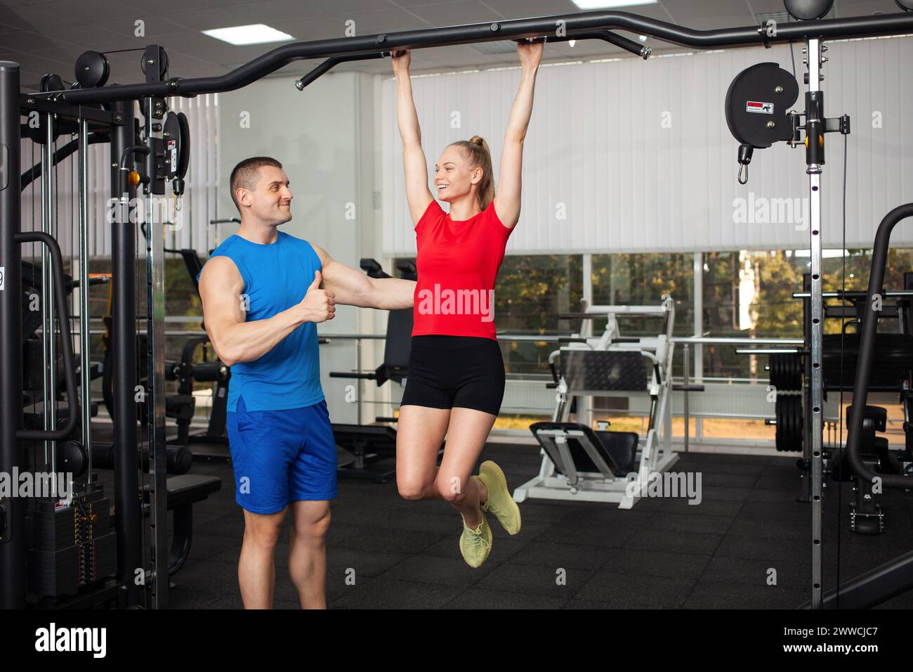 teenager performs an exercise on a simulator in gym. girl hangs on ...