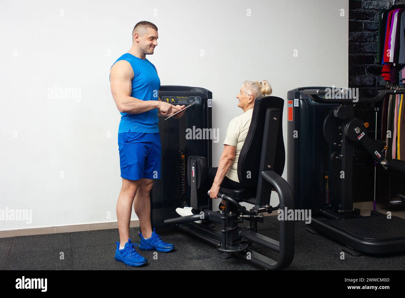 A young handsome coach man shows the older woman how to perform ...