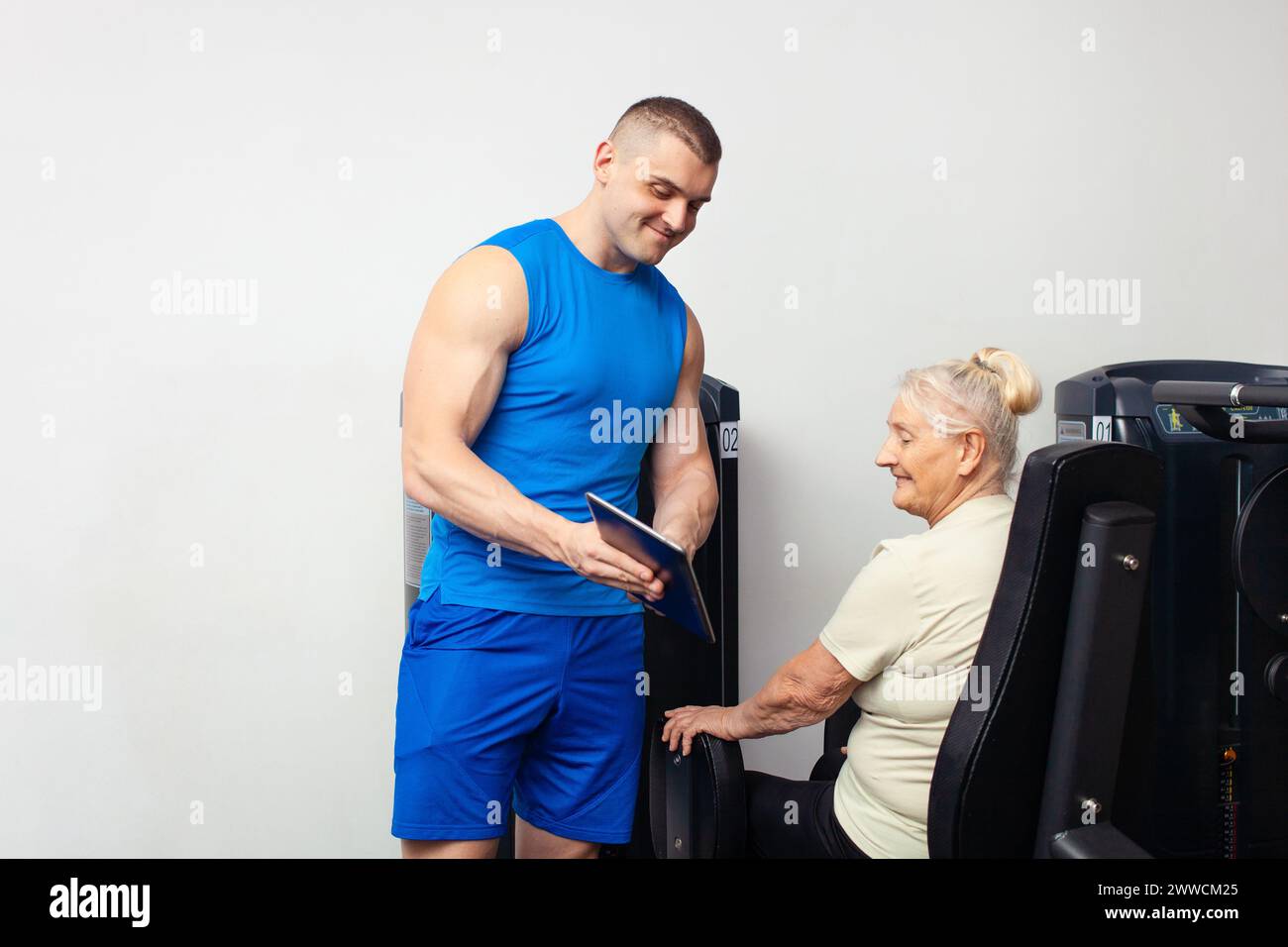 A young handsome coach man shows the older woman how to perform ...