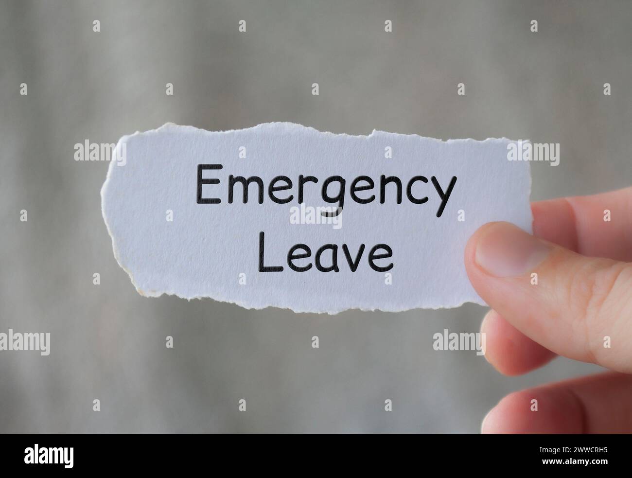 Hand holding torn paper with Emergency Leave text with blur background ...