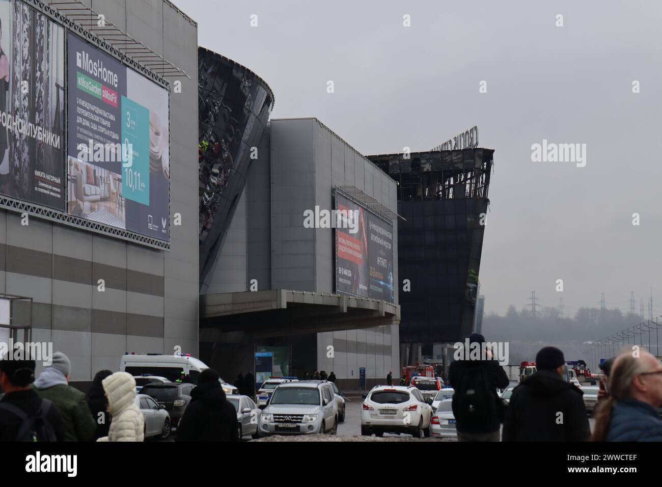 Moskau, Russia. 23rd Mar, 2024. People walk past the badly damaged ...