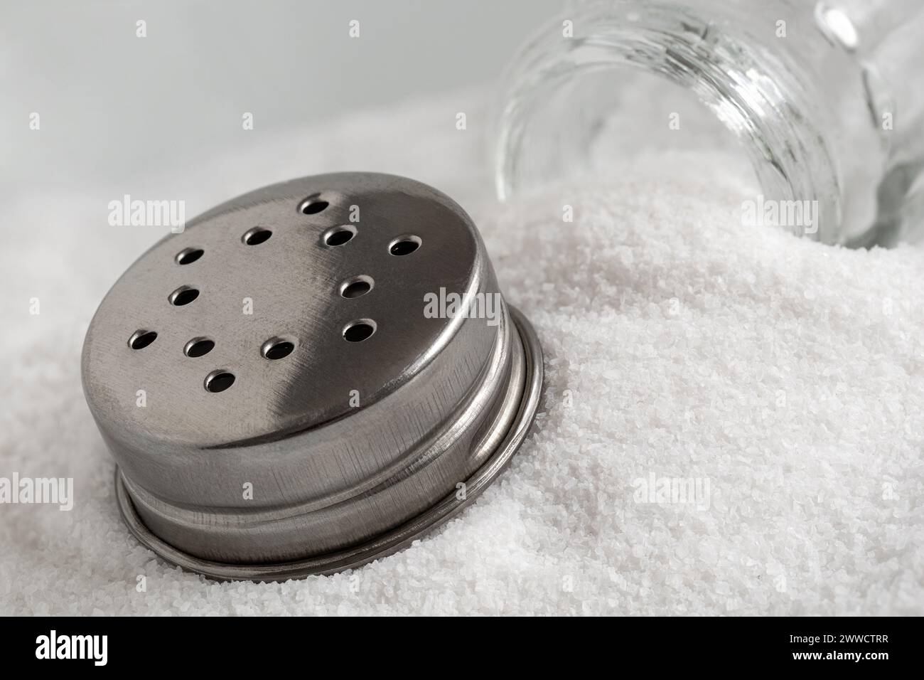 Glass salt shaker and metal lid lying on top of sea salt Stock Photo ...