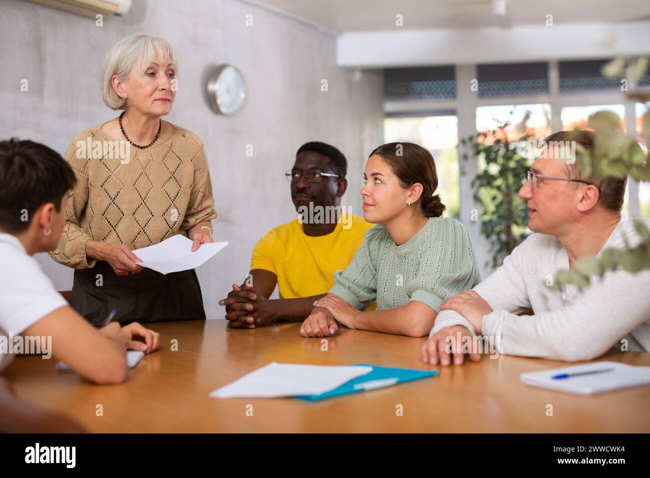 Elderly manager holds round table meetings for employees of different ...