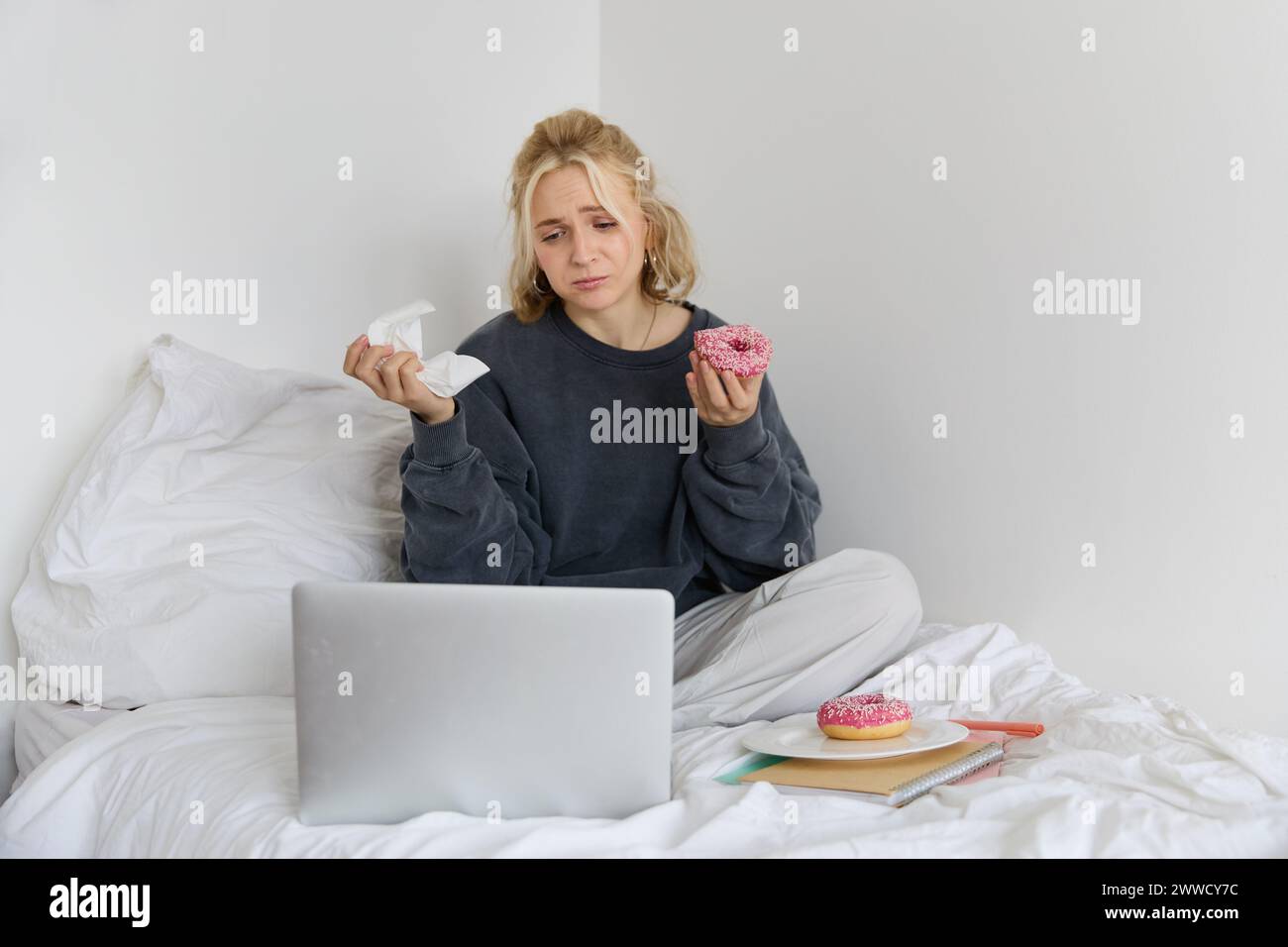 Portrait of sad, crying young woman, staying at home, sitting in bed ...